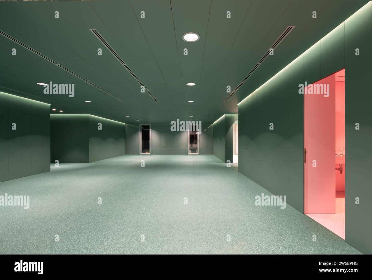 Illuminated passage with green walls and glass doors with pink opened ...