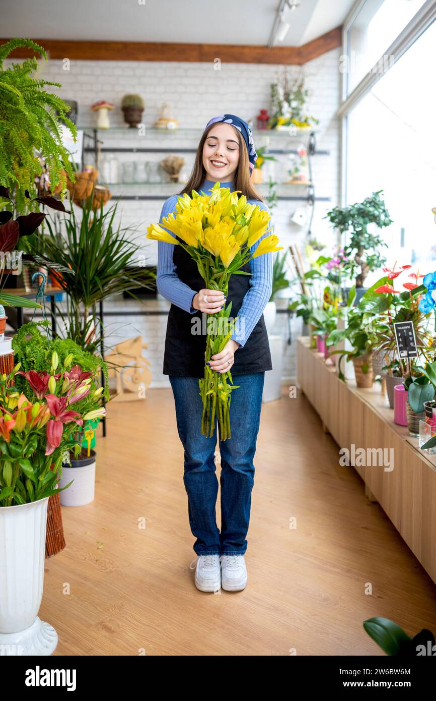 Smiling young female florist in casual clothes and bandana with eyes ...