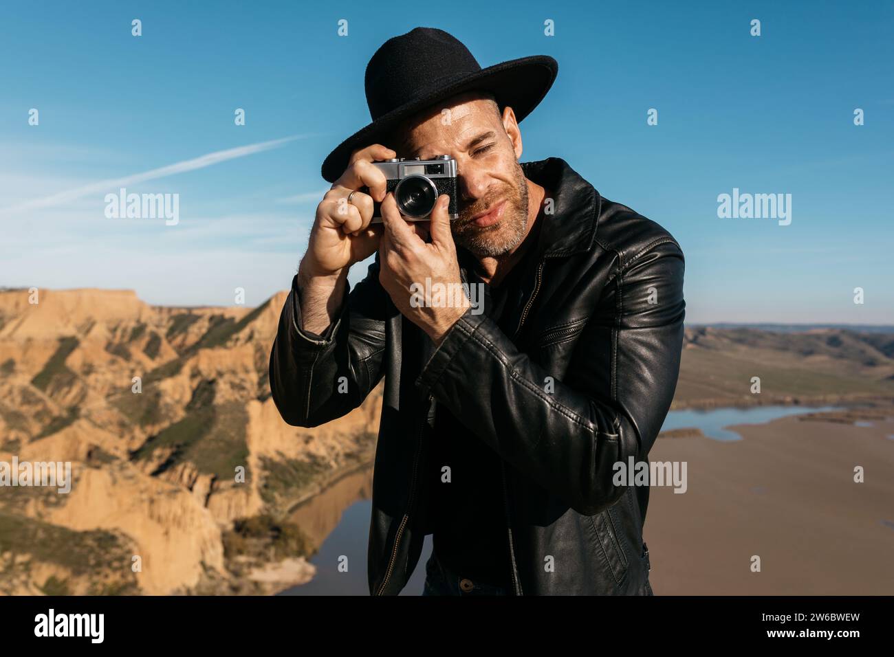 A trendy travel photographer wearing a black hat and leather jacket ...