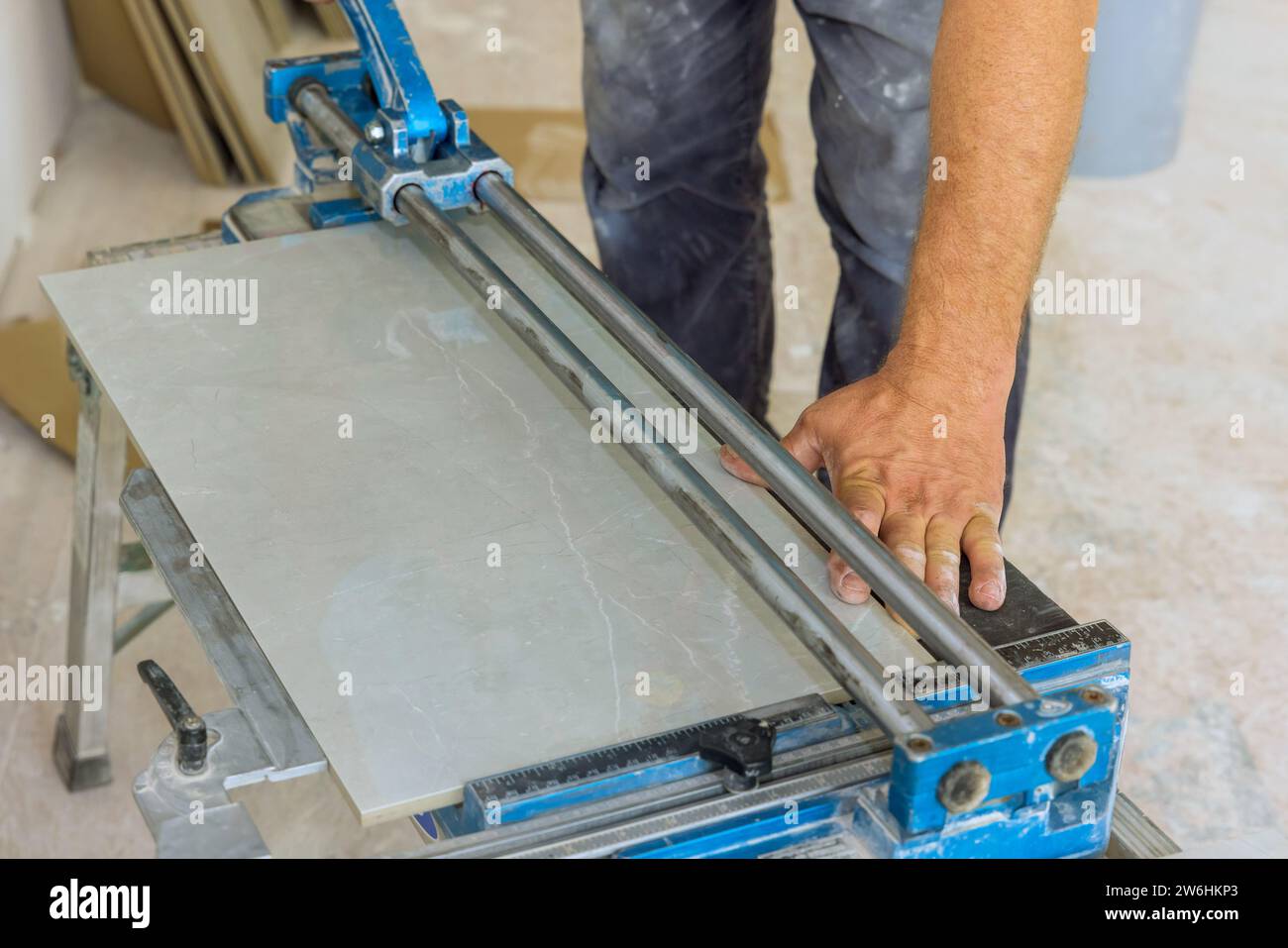An employee of construction company uses tile cutting hand machine to ...
