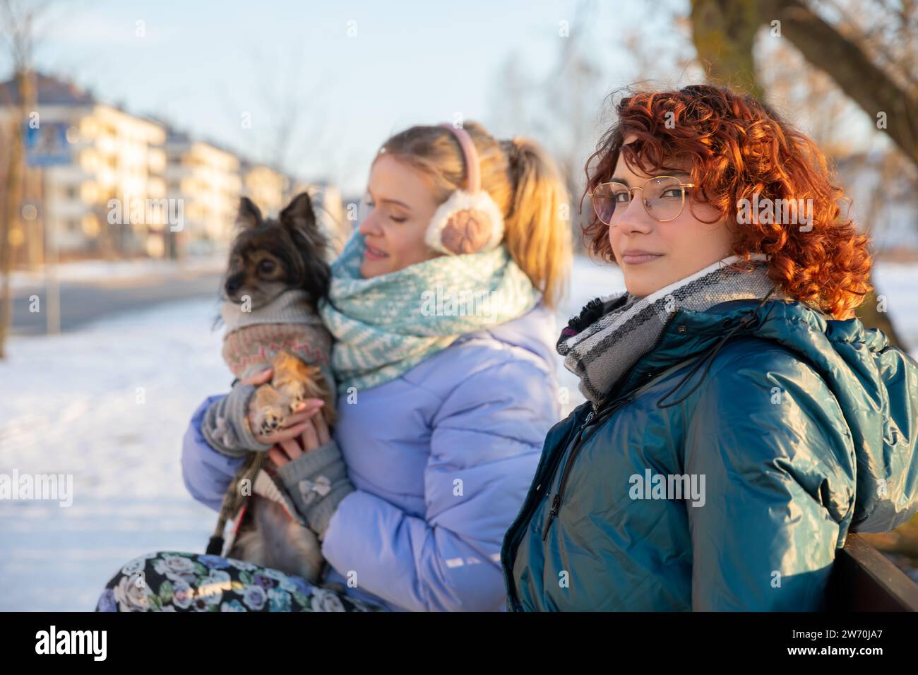 Two women wait for a bus in winter Stock Photo - Alamy