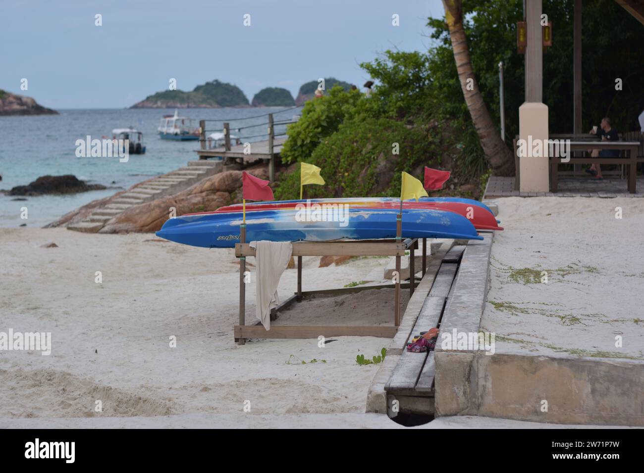 colourful kayak stack on the rack near beach with bright blue sky as ...