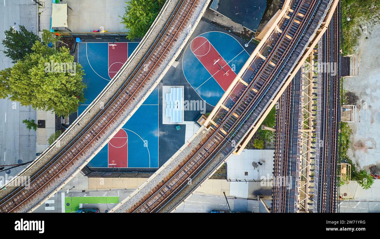 Empty train track, railroad transit, transportation bridges above basketball courts aerial ...