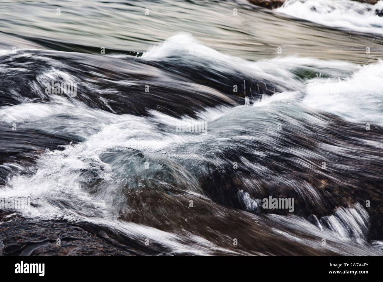 Long exposure, abstract white swirling water rushing over the rocks ...