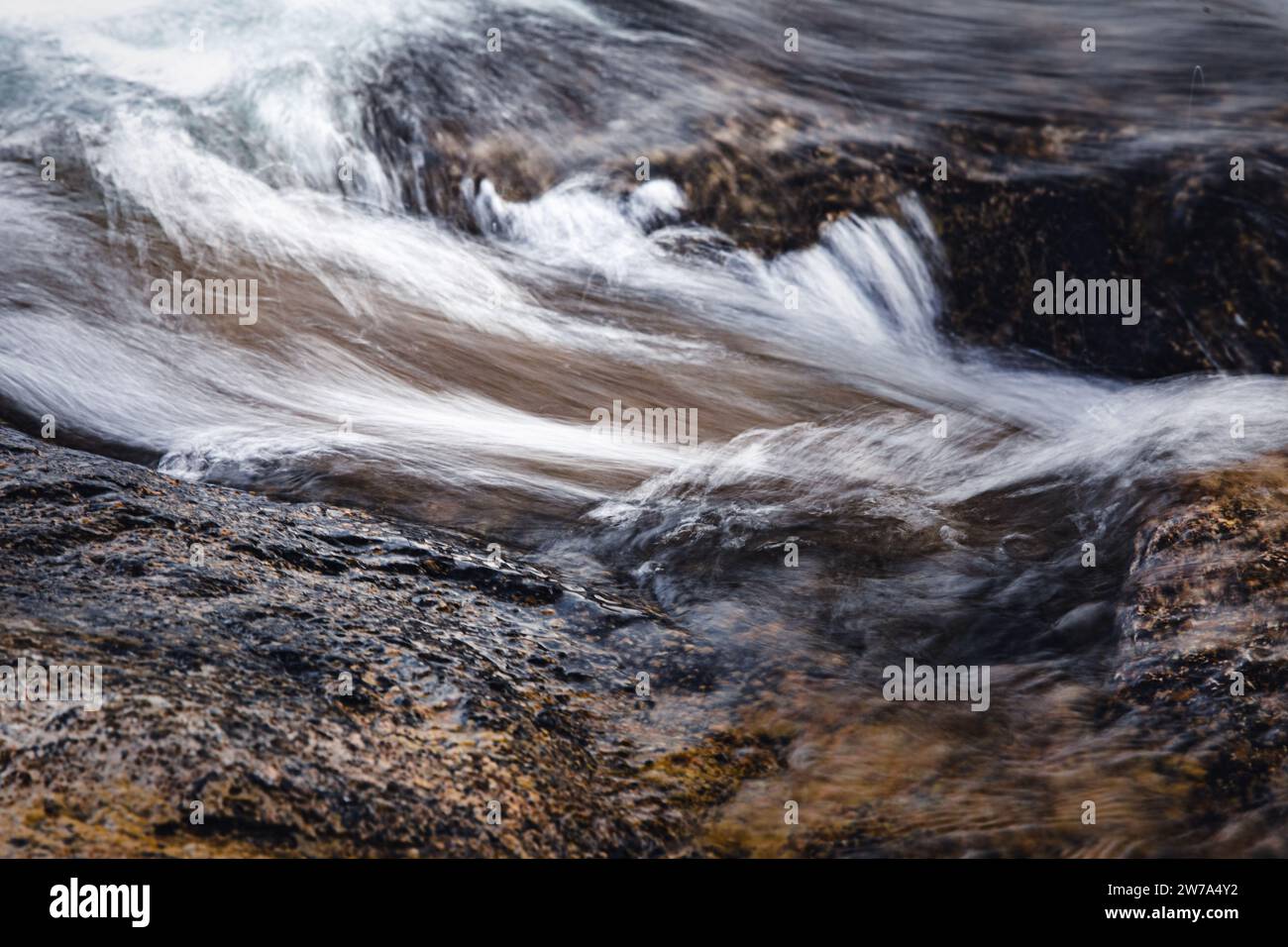 Long exposure, abstract white swirling water rushing over the rocks ...