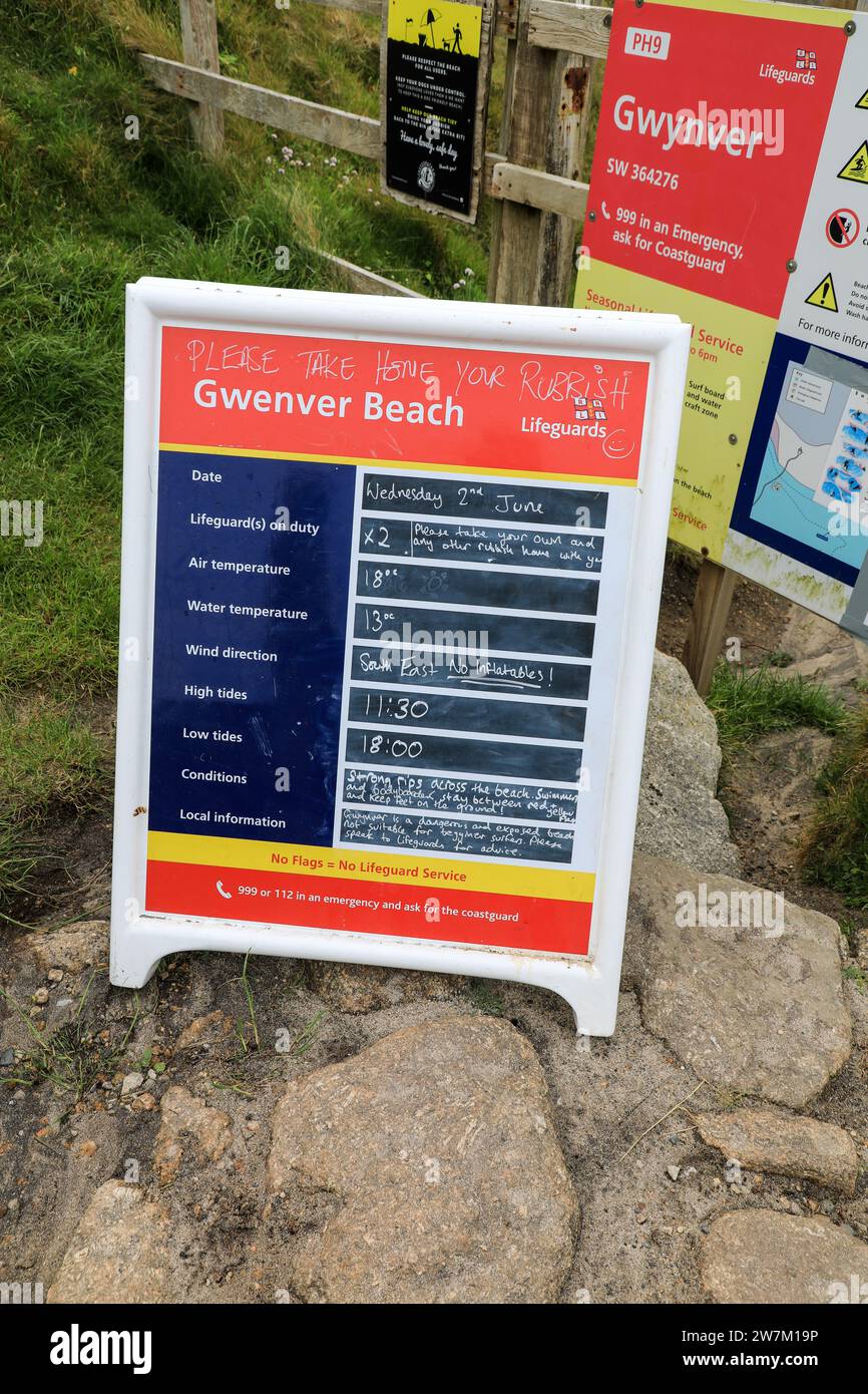 A sign board with tide and weather information on Gwynver Beach or ...