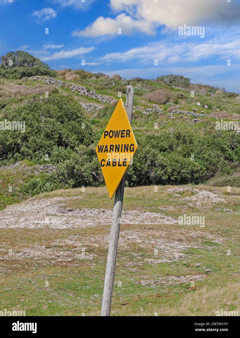 A diamond shaped yellow warning sign saying "Power Cable Warning ...