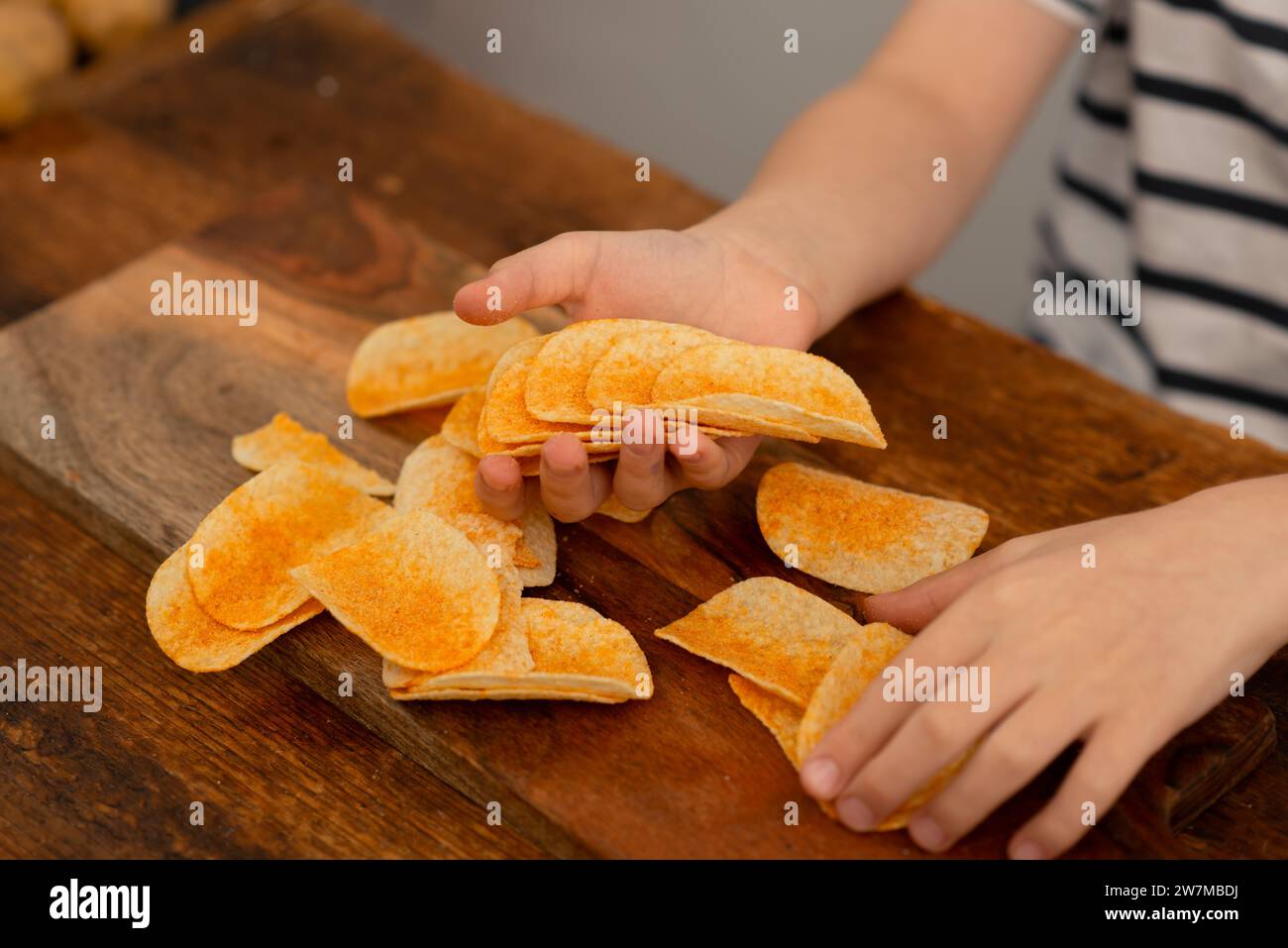Engaging in snack play, a kid's hands with potato chips on wood Stock ...