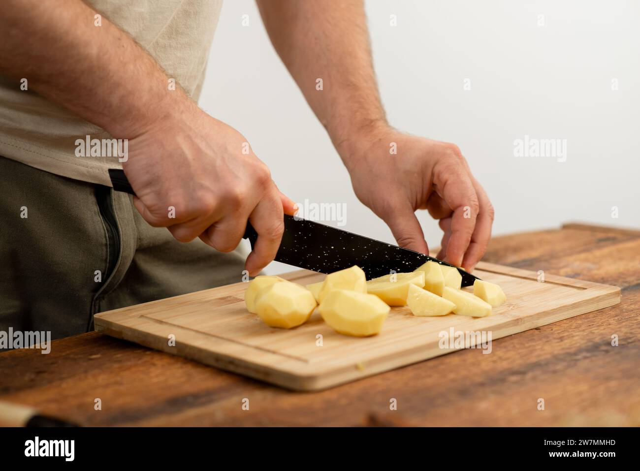 Preparing ingredients: dicing potatoes on a bamboo chopping board Stock ...
