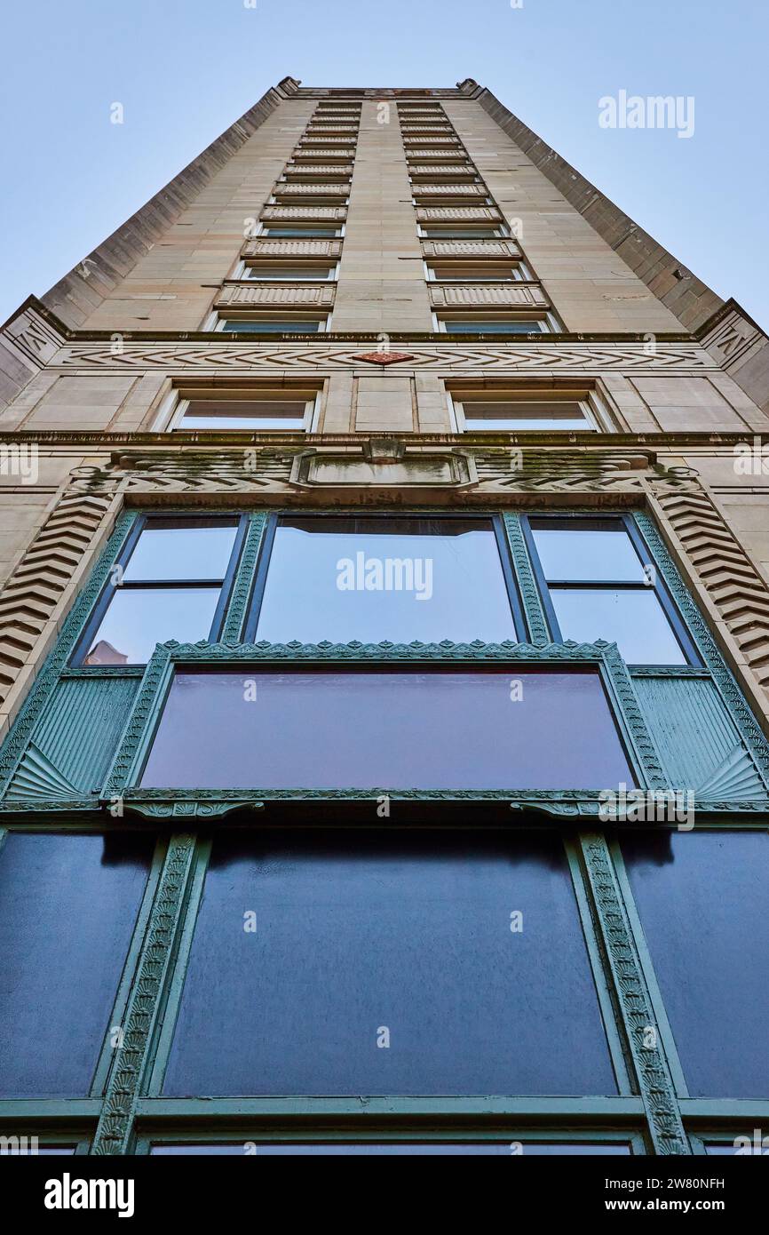 Upward view of side of skyscraper building with windows reflecting blue ...