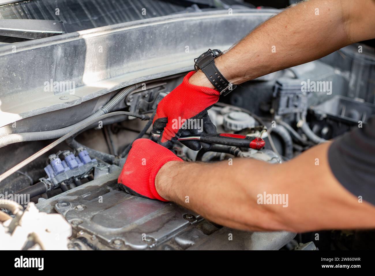Car repairs. An auto mechanic unscrews the gas distribution mechanism ...
