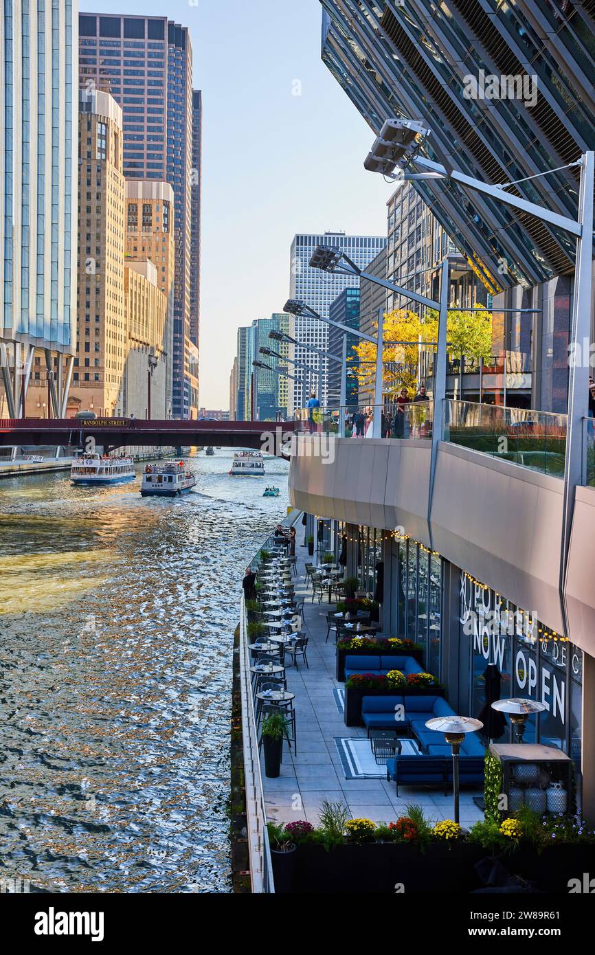 Waterside patio on Chicago canal with tour boats passing under bridge ...