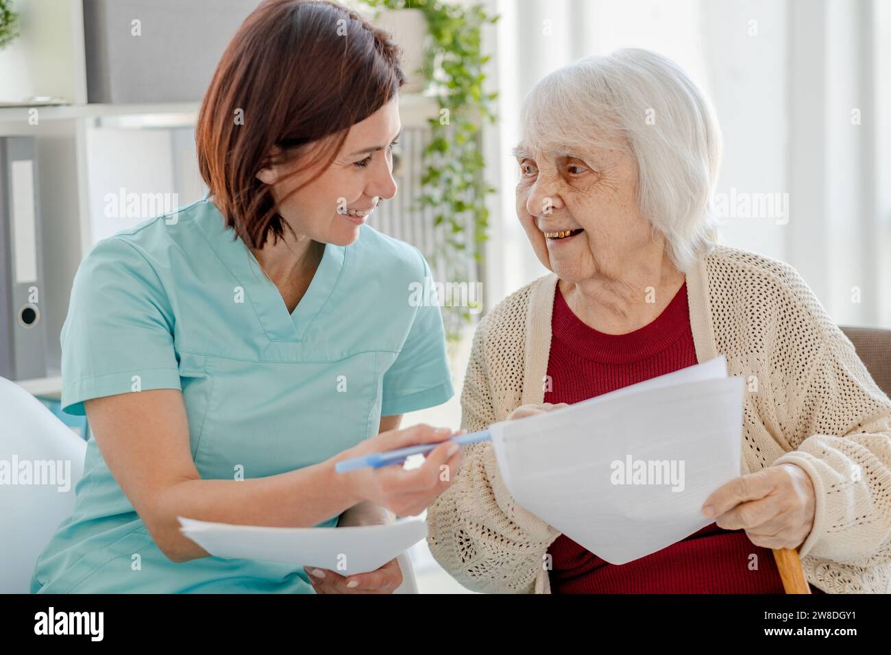 Smiling Nurse Gives Elderly Woman Documents To Read In Doctor'S Office ...
