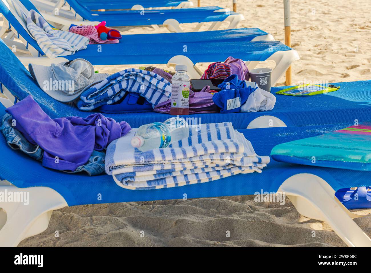 Towels and beach items on sun loungers on the sandy shores of the ...