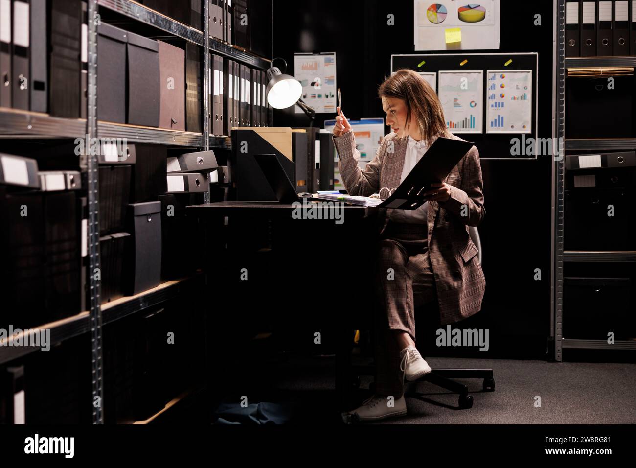 Inspector reading police report, working late at night at criminal case ...