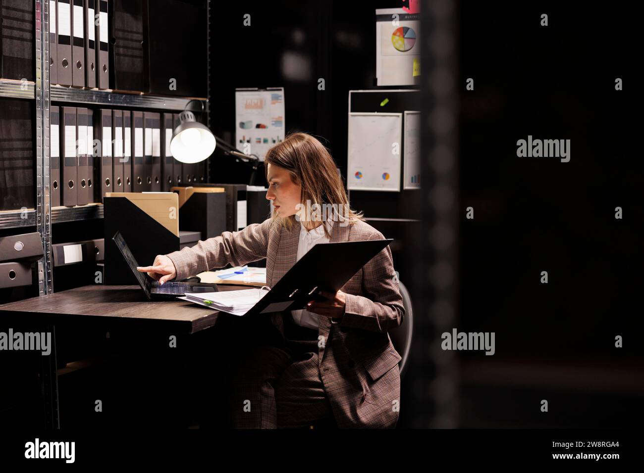 Investigator reading criminology files, working late at night at ...