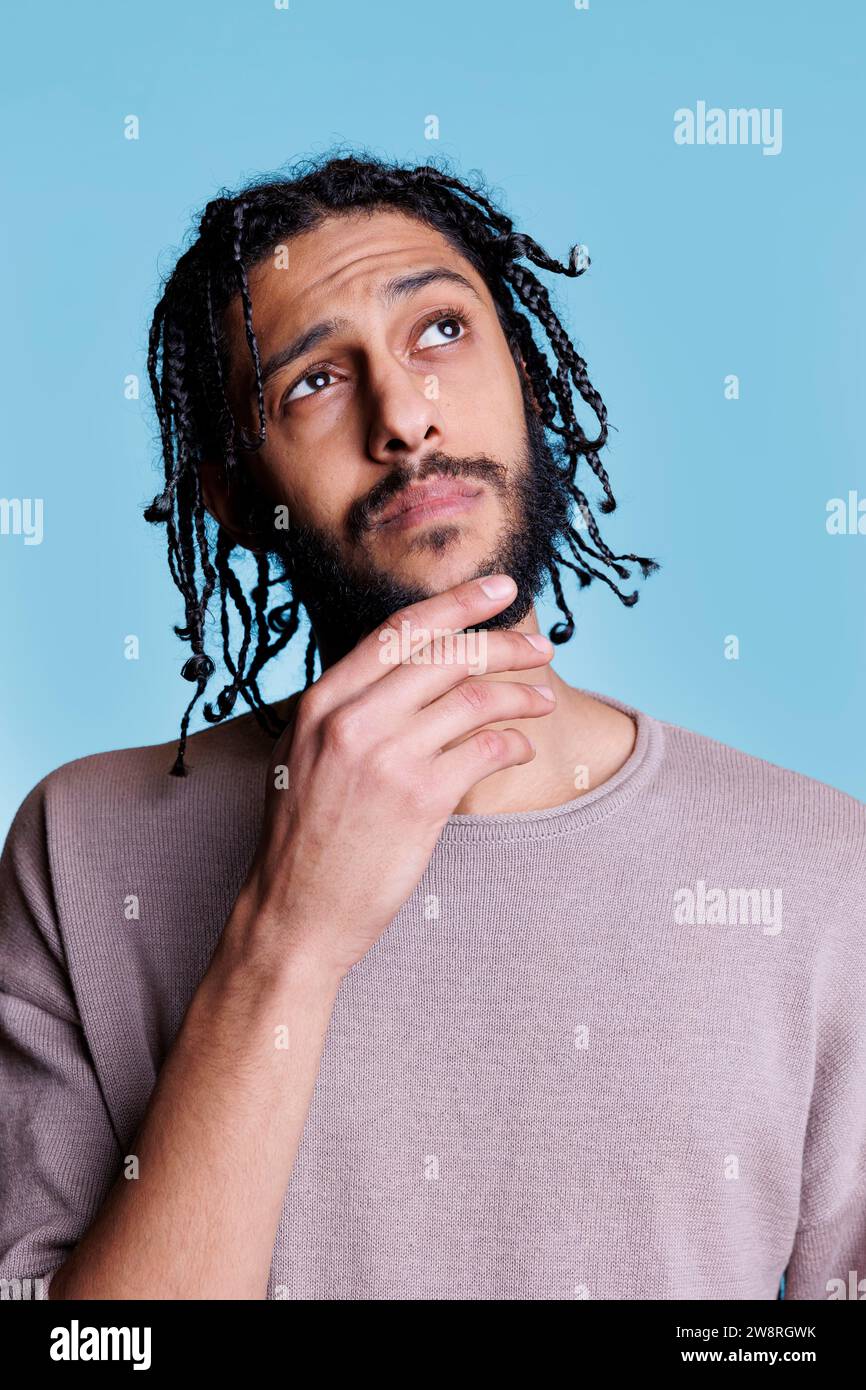 Arab handsome man thinking and rubbing chin while looking away with ...