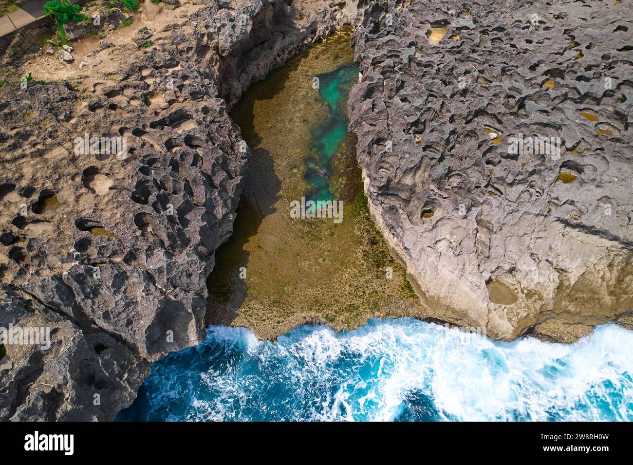 A cliff broken by the wave of the ocean. Natural azure bathing pool in ...