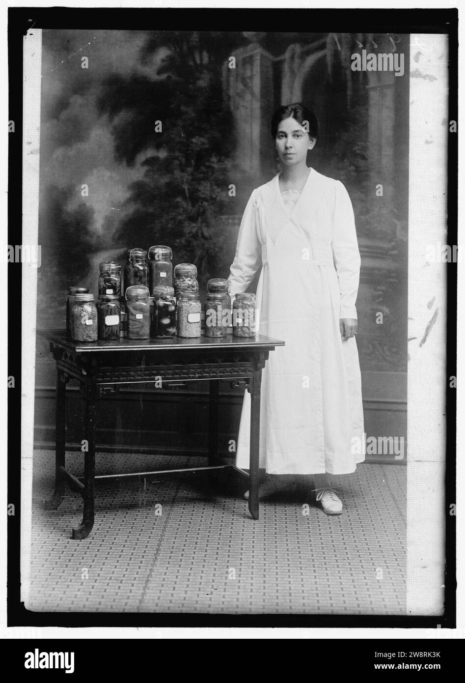 Woman standing next to table holding a display of preserved food in ...