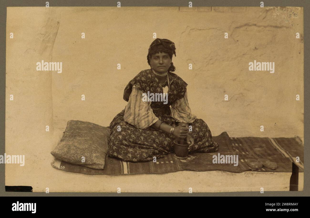Woman, full-length portrait, seated on rug on ground, facing front ...