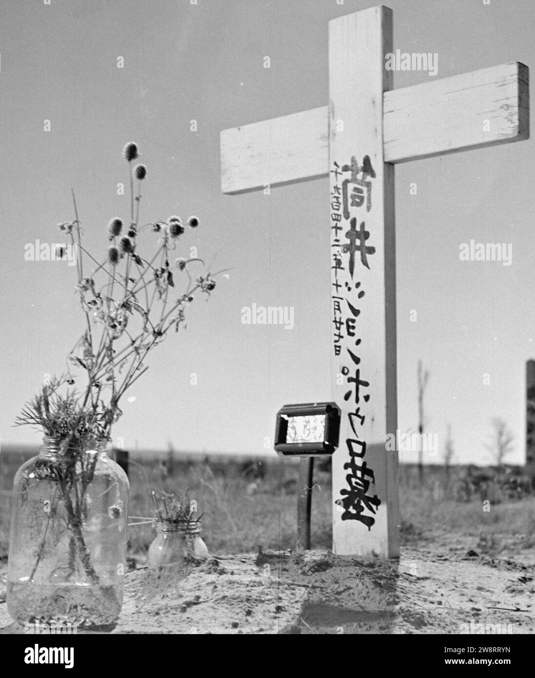 Wooden cross with Japanese writing and wilted flowers in October 1945 ...