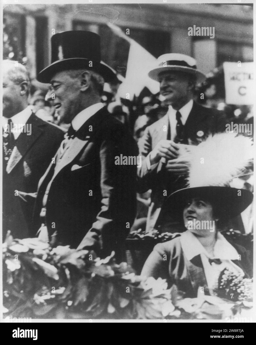 Woodrow Wilson, in a top hat, standing while his wife Edith Bolling ...