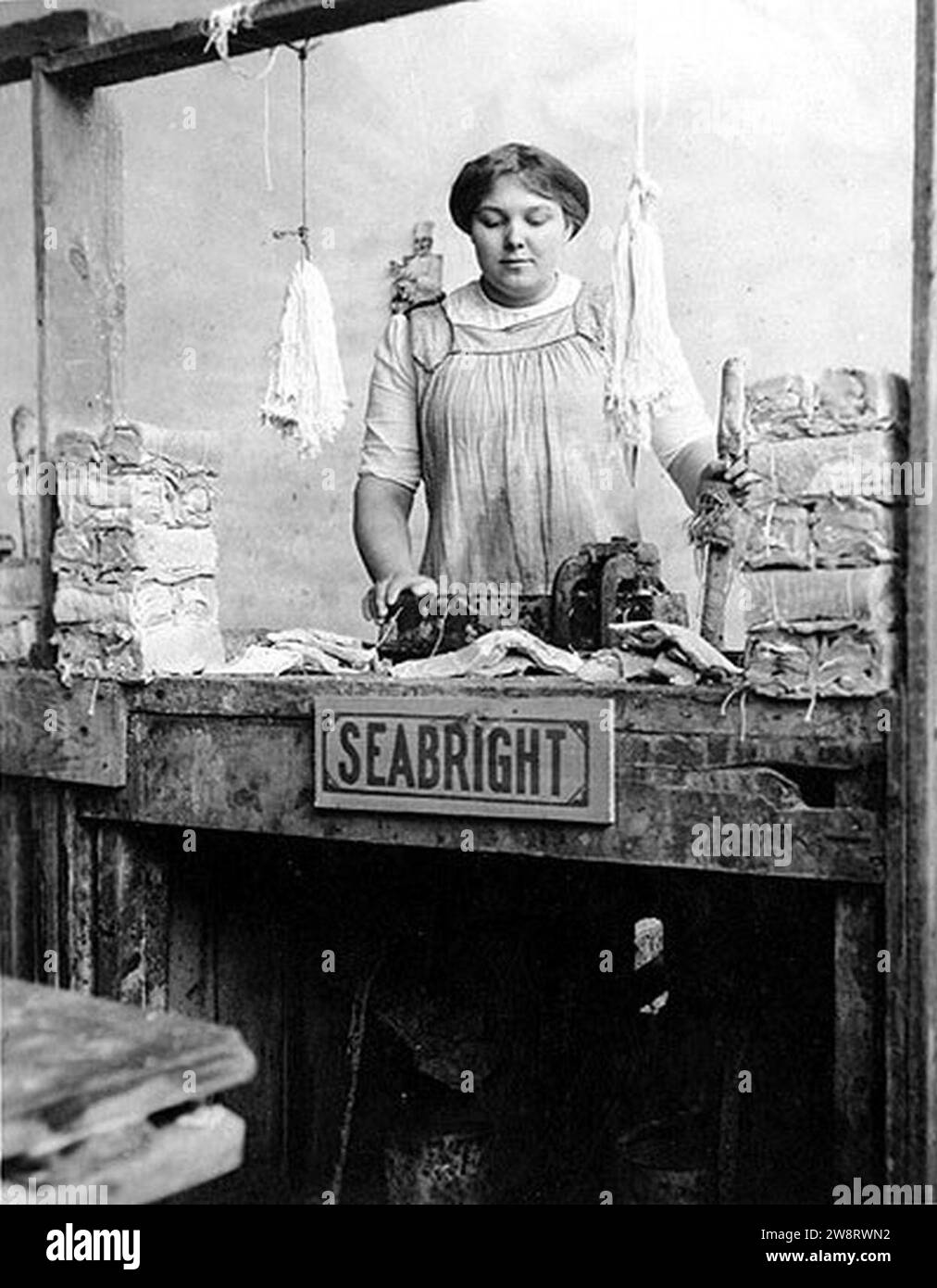 Worker making cod bricks, unidentified fish processing plant, probably ...