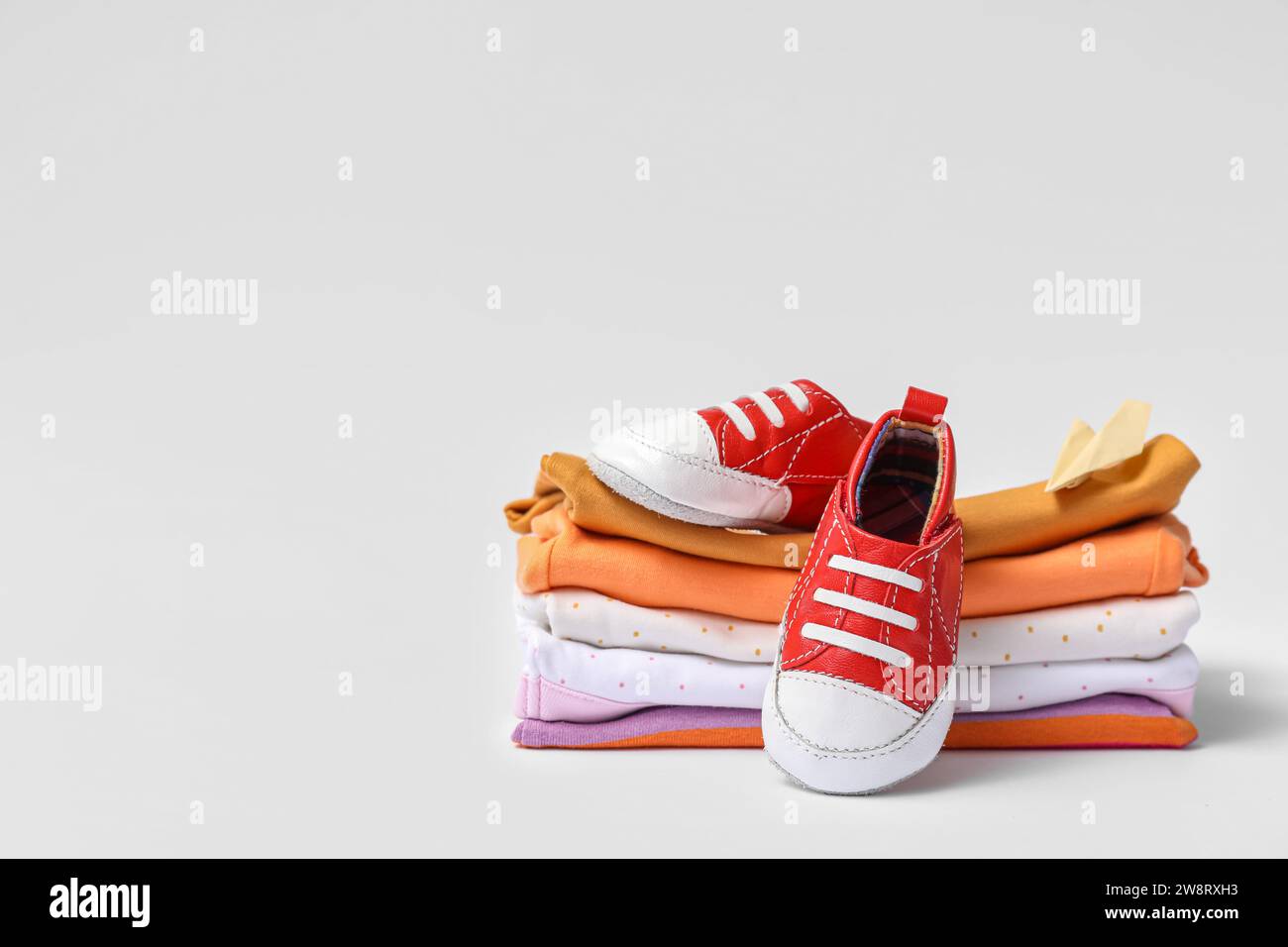 Stack of baby clothes and booties on white background Stock Photo - Alamy