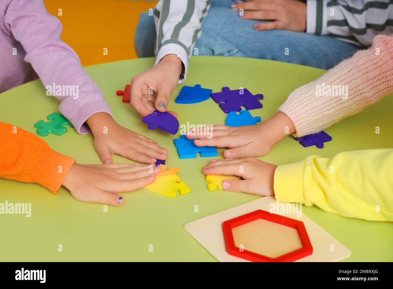 Little children with nursery teacher doing puzzle at table in ...