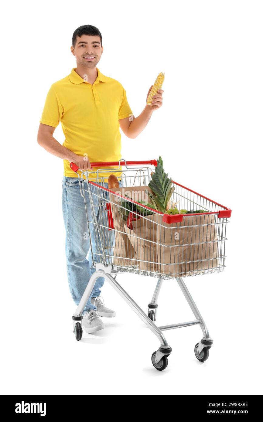 Young man with shopping cart and grocery bags holding corn cob on white ...