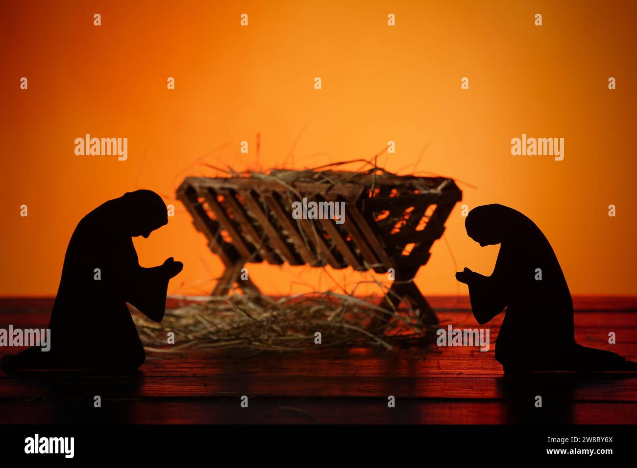 Christmas nativity scene of Joseph and Mary near manger against orange ...