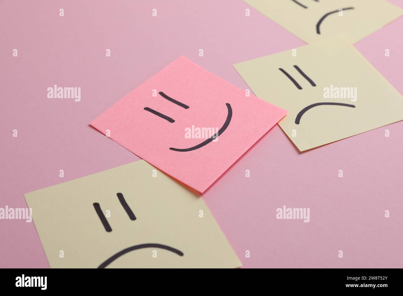 Choice concept. Sticky note with happy emoticon among beige papers with ...