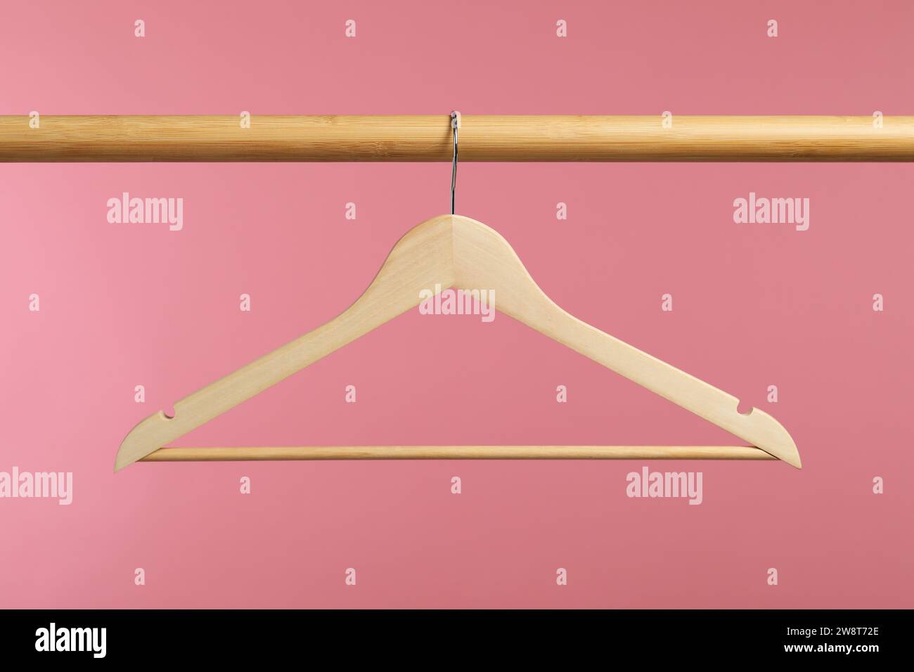 Empty clothes hanger on wooden rack against pink background Stock Photo ...