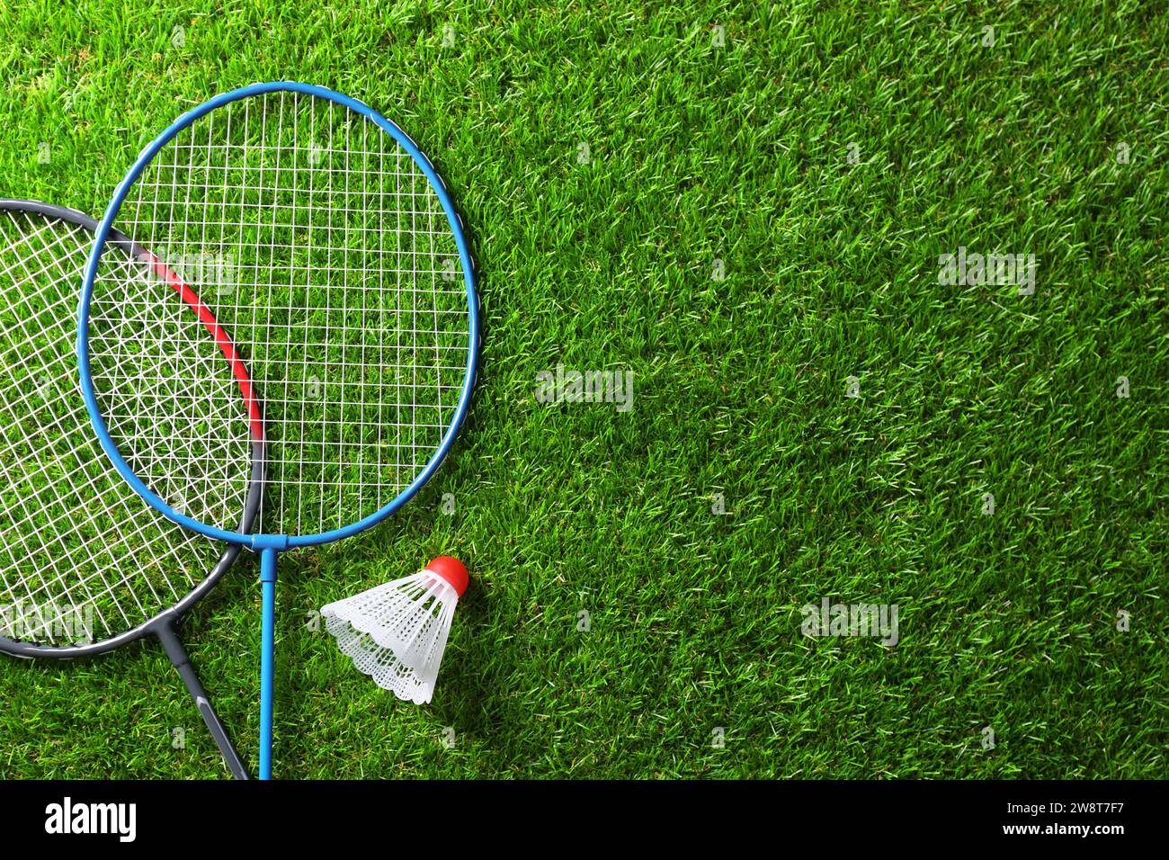 Two badminton rackets and shuttlecock on green grass, top view with ...