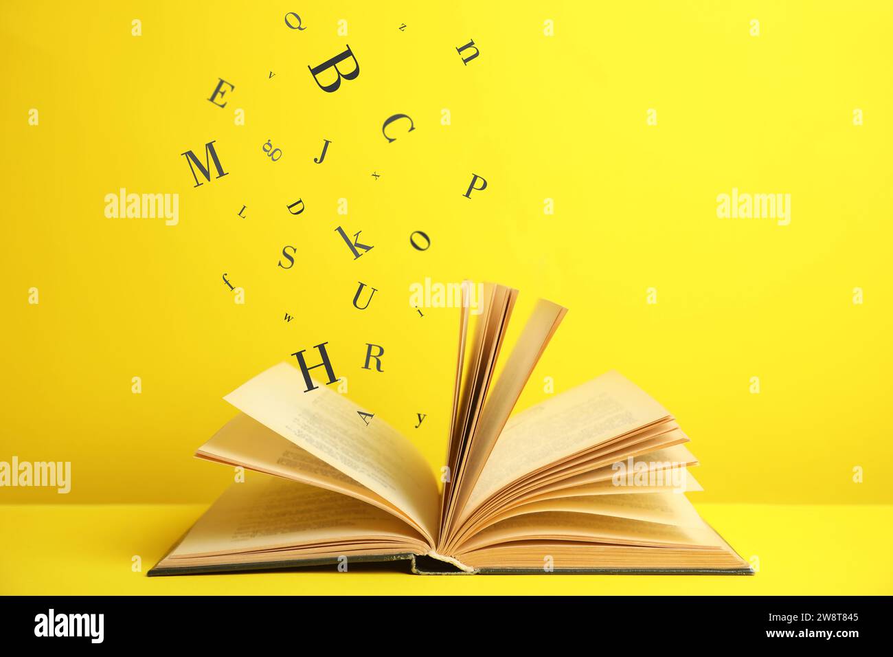 Open book with letters flying out of it on yellow background Stock ...