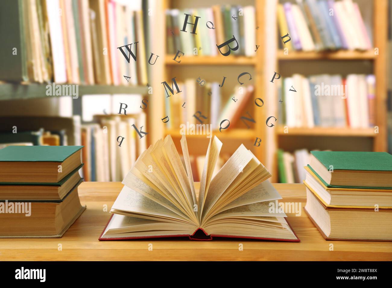 Open book with letters flying out of it in library Stock Photo - Alamy