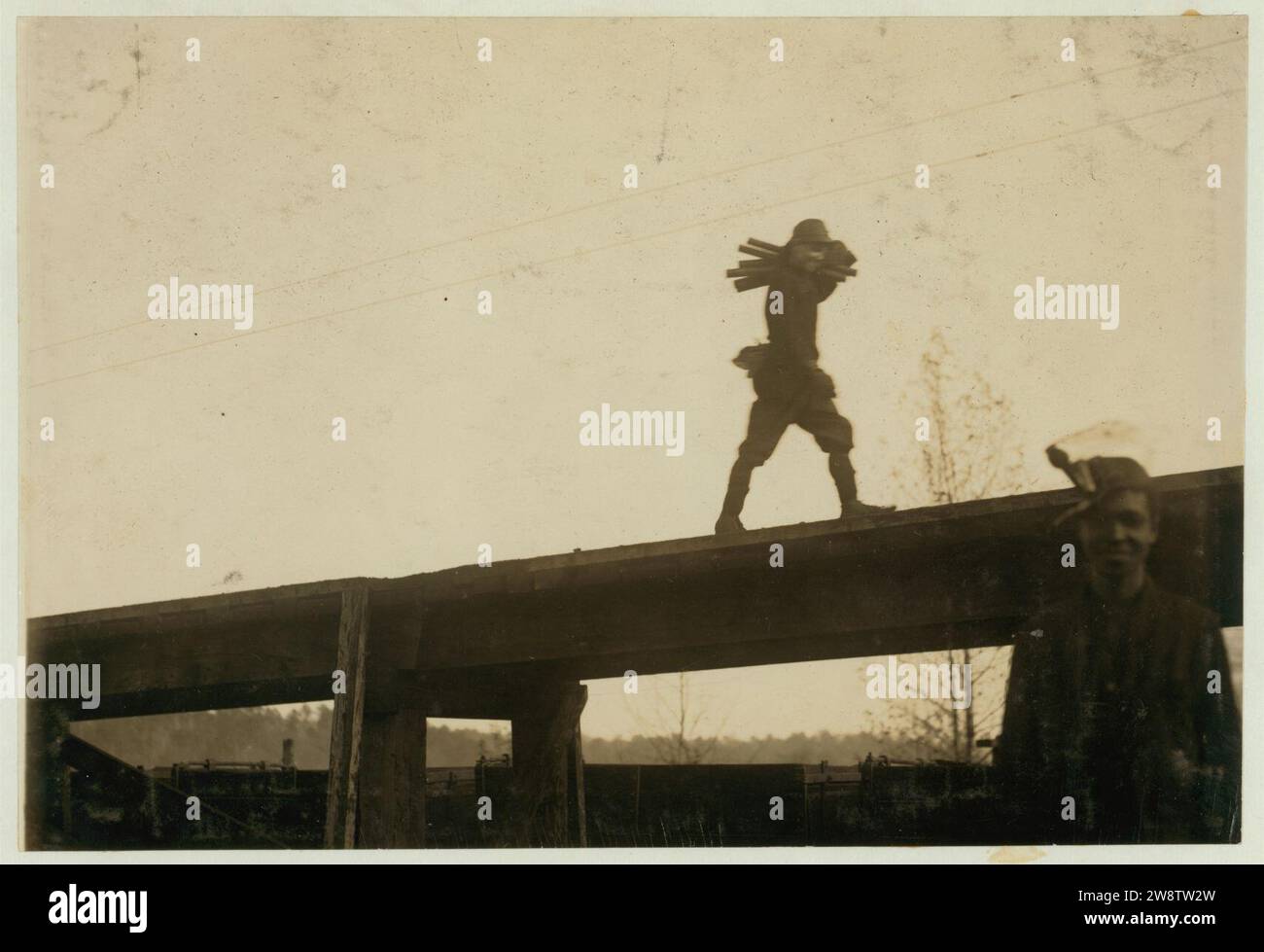 Young boy carrying armful of steel rods, 'spragging irons' along the ...