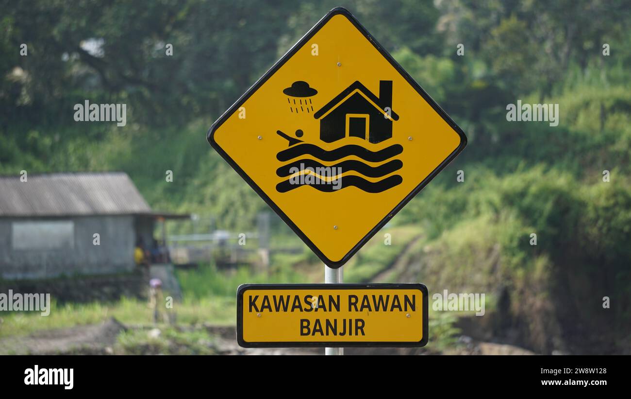 Yellow sign with a natural background. Kawasan rawan banjir means flood ...