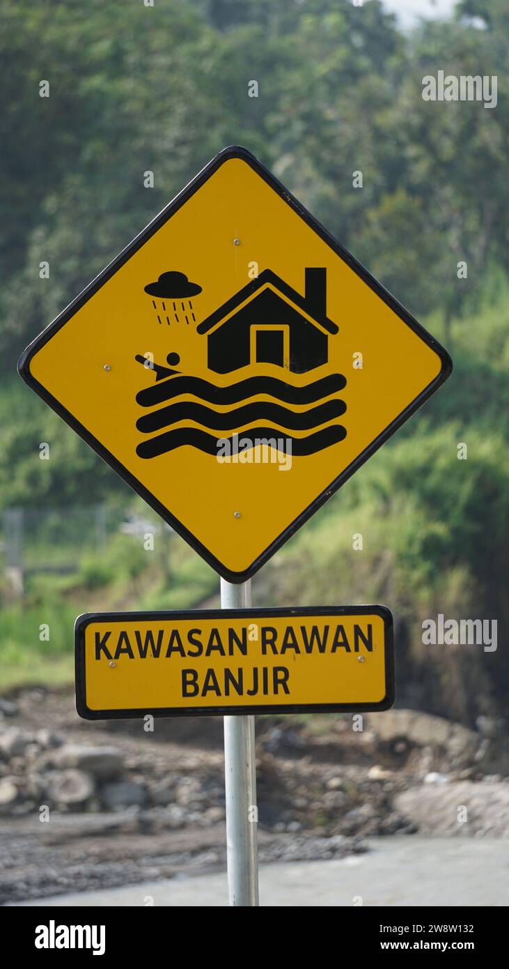 Yellow sign with a natural background. Kawasan rawan banjir means flood ...