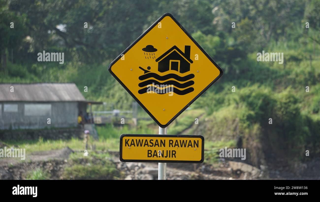 Yellow sign with a natural background. Kawasan rawan banjir means flood ...