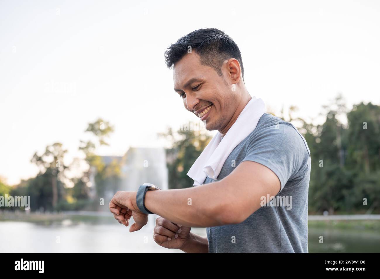 A happy, fit Asian man in sportswear is checking his calories burning ...