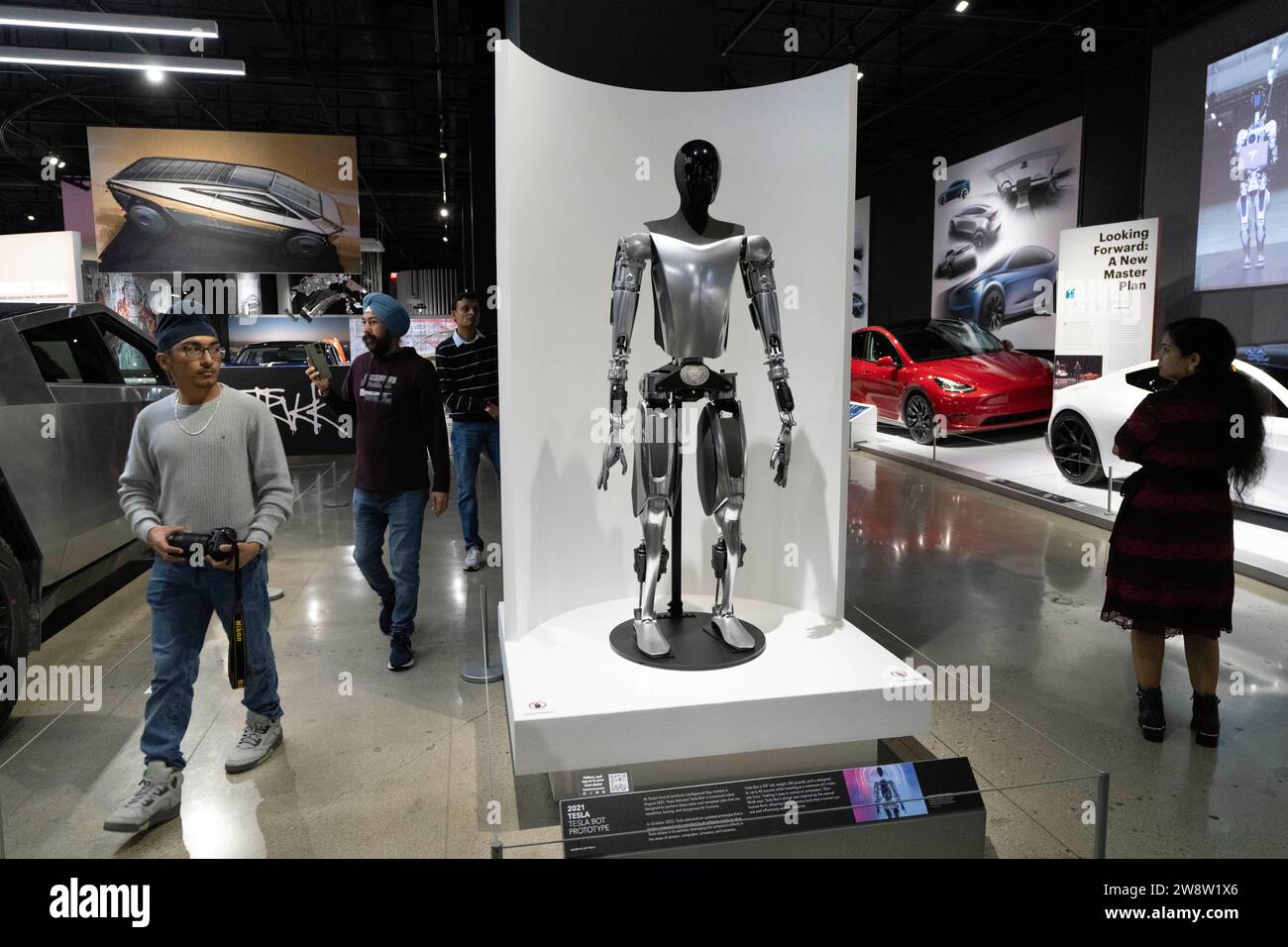 Visitors walk past a 2021 Tesla Bot prototype on display at the ...