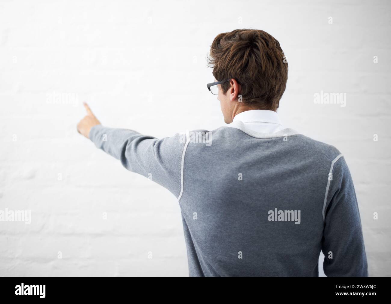 Man, back and pointing to mockup space by wall background, presentation ...