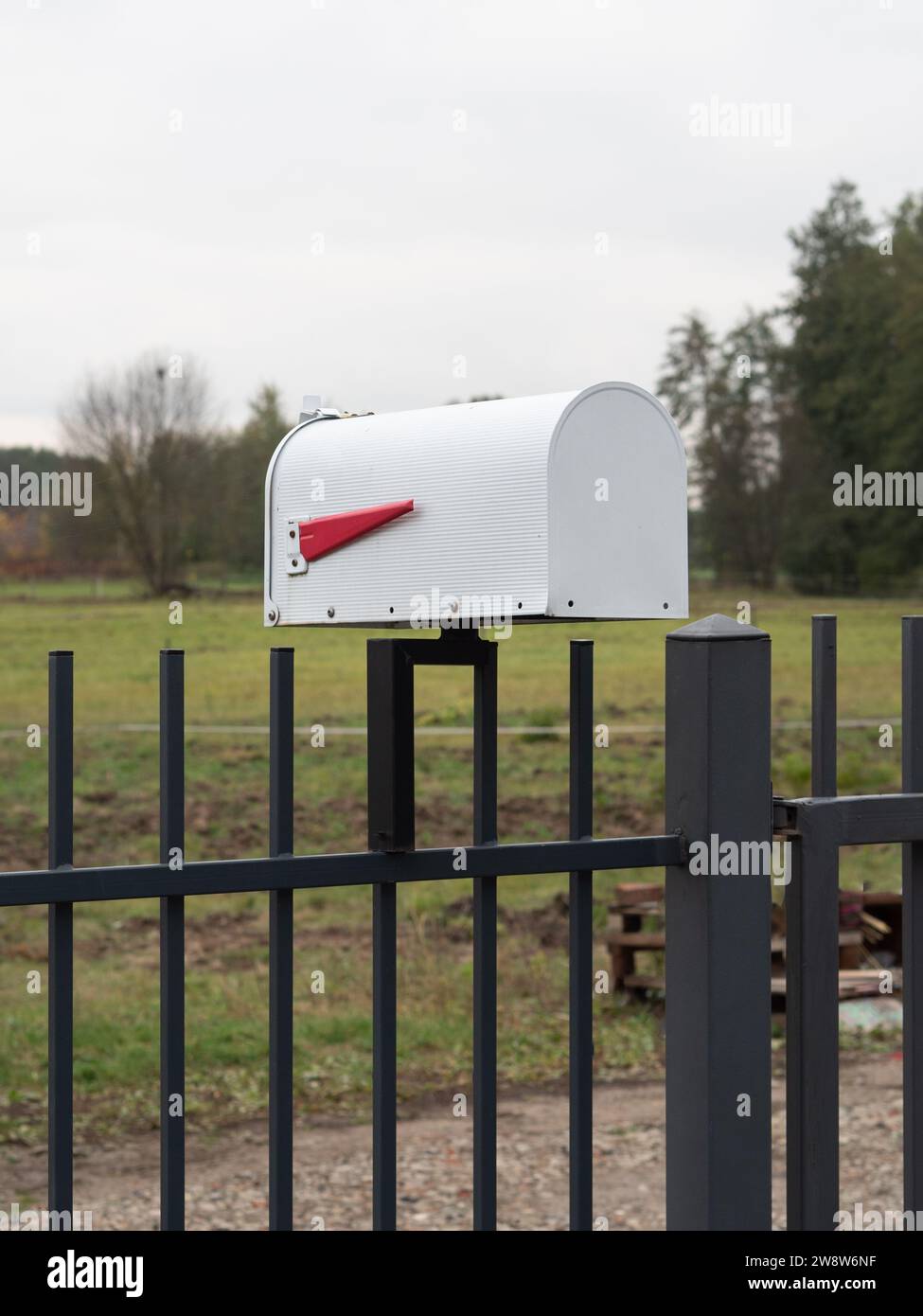 Vertical View of a White Mailbox and a metal fence at a Countryside ...