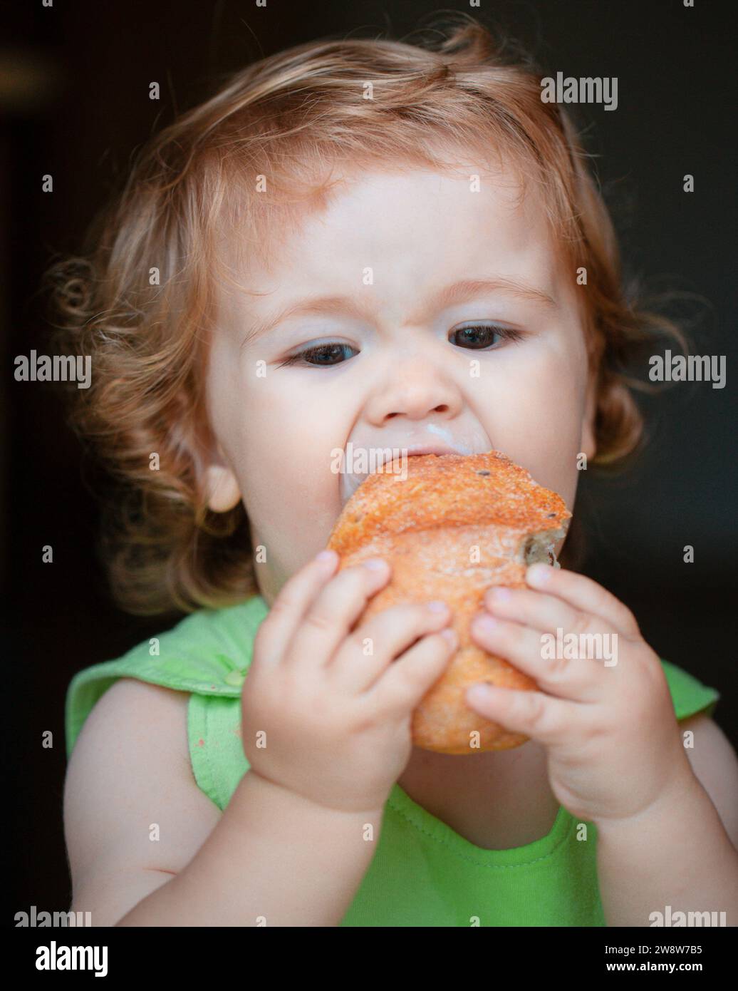 Cute Baby boy is very greedy eating a piece of white bread, hungry and ...