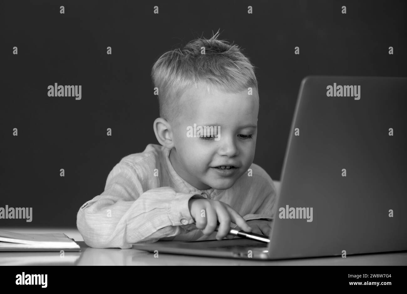 Elementary school kid working in computer class. Funny blonde pupil on ...
