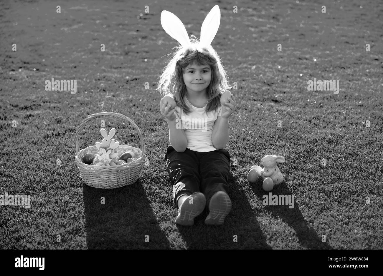 Child with easter eggs and bunny ears laying on grass. Happy Easter ...