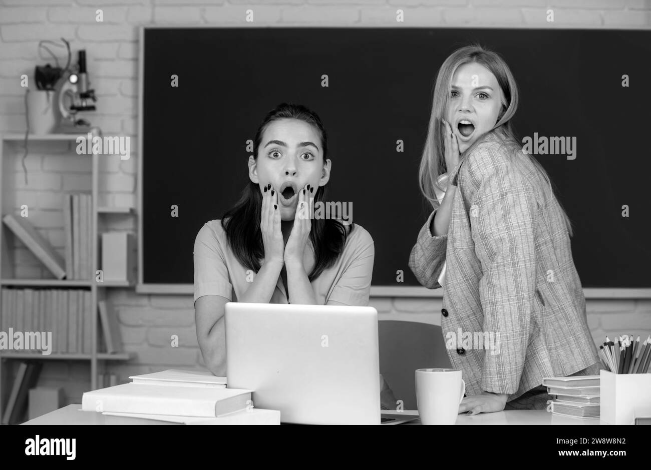 Two surprised students girls friends in classroom at school college or ...