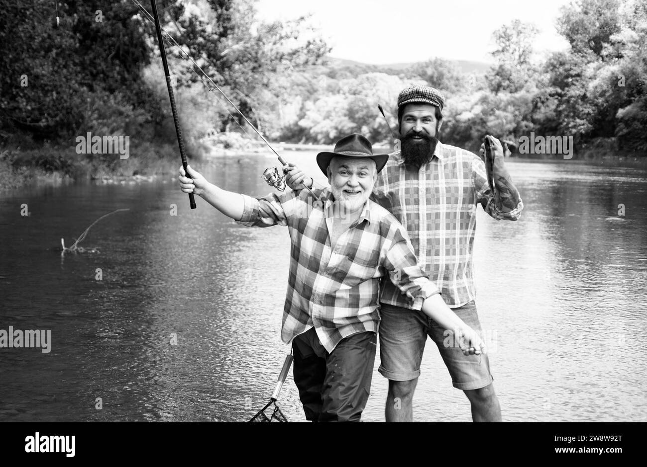 Two men friends fisherman fishing on river. Old father and son with rod ...