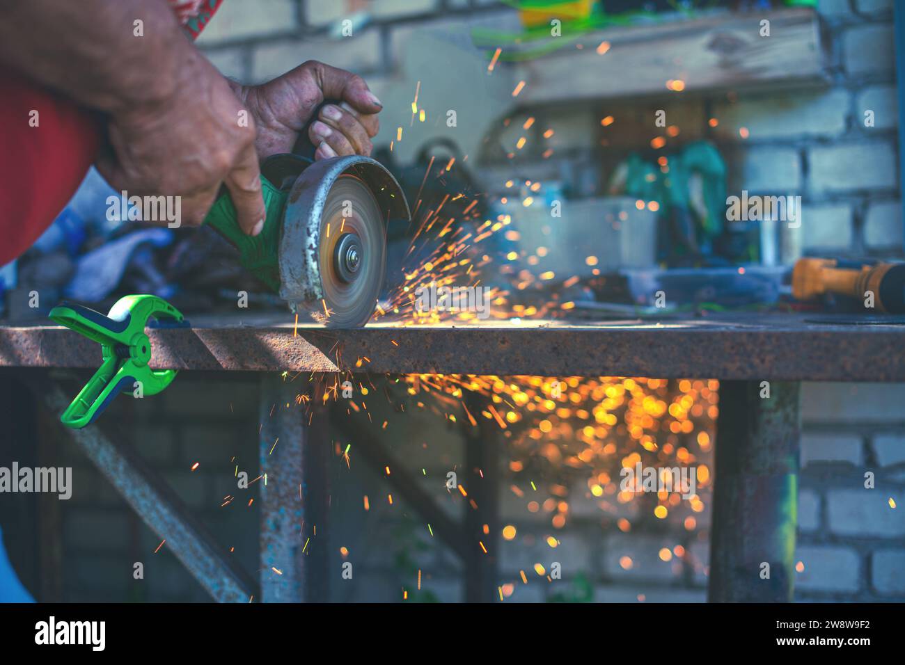 Hands of the master saw the metal with a grinder. metal works in the ...